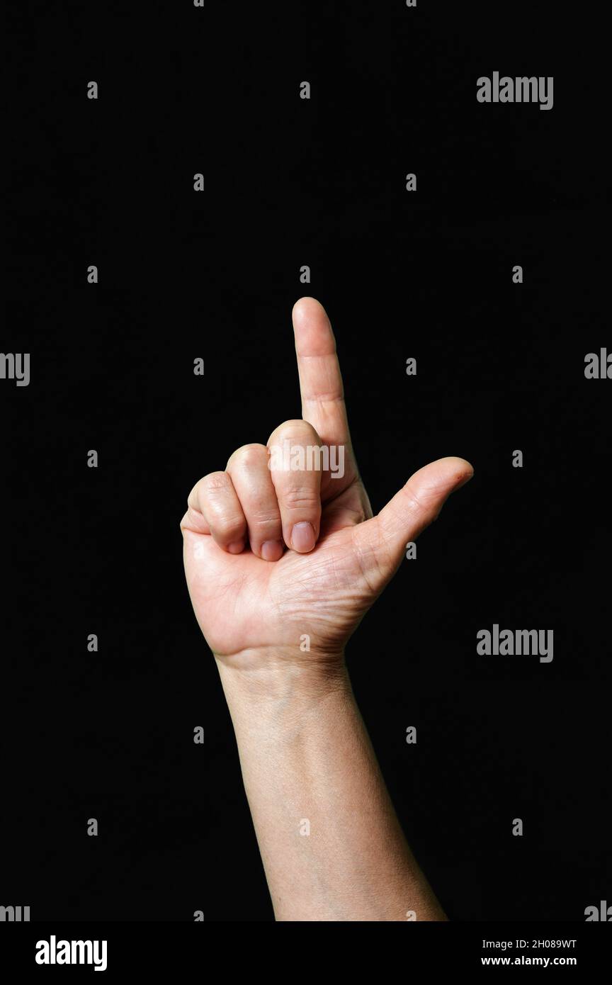 Vertical shot of a hand showing the letter L on a dark background Stock ...