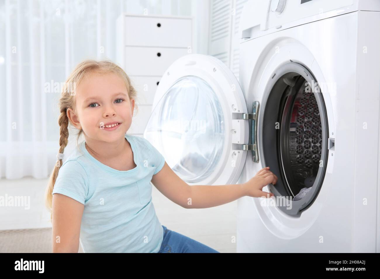 Adorable little girl doing laundry at home Stock Photo - Alamy