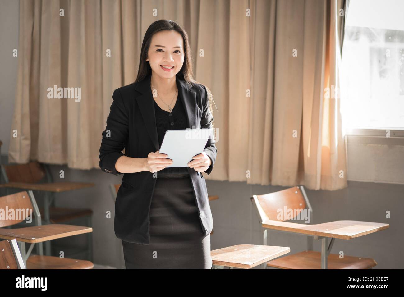 Female teacher in a black business suit and with a tablet in a ...