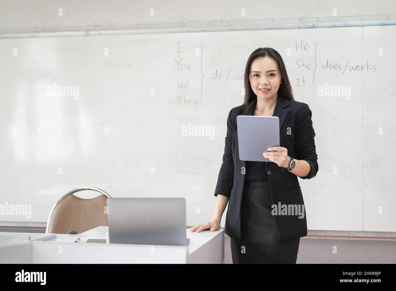 Female teacher in a black business suit and with a tablet in a ...