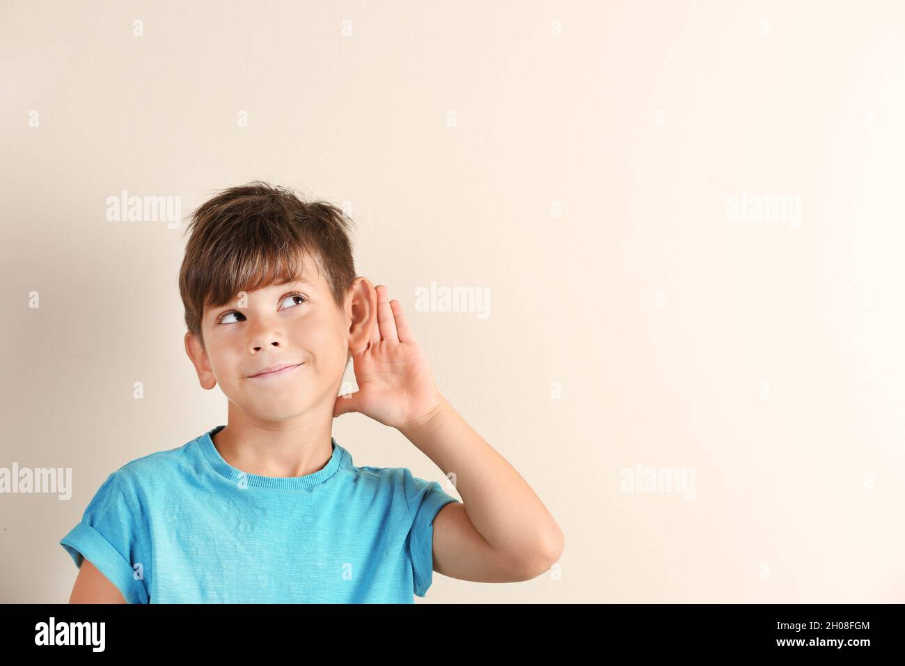 Cute little boy with hearing problem on light background. Space for ...