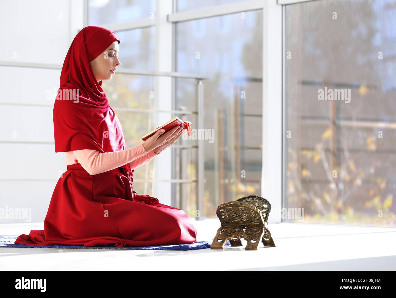 Muslim woman in hijab reading Koran indoors. Space for text Stock Photo ...