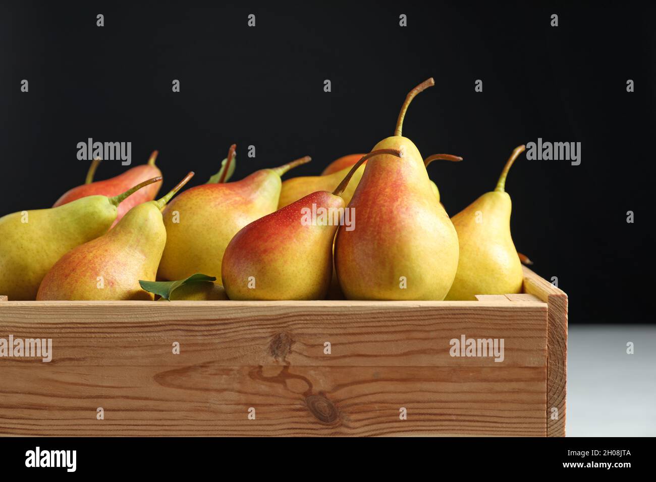 Wooden crate with ripe pears on black background, closeup Stock Photo ...