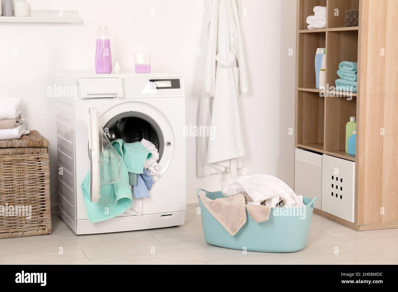 Washing machine with dirty clothes and towels in laundry room Stock ...