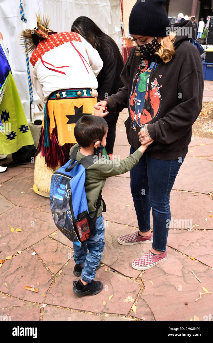 A Native American woman and her young son hold hands as they wait for ...