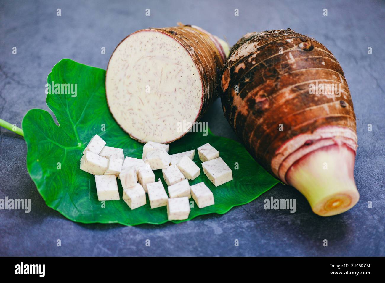 Taro root with half and slice cubes on taro leaf and wooden background ...