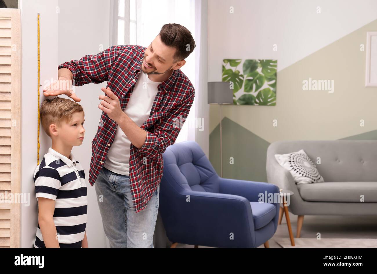 Young man measuring his son's height at home Stock Photo - Alamy