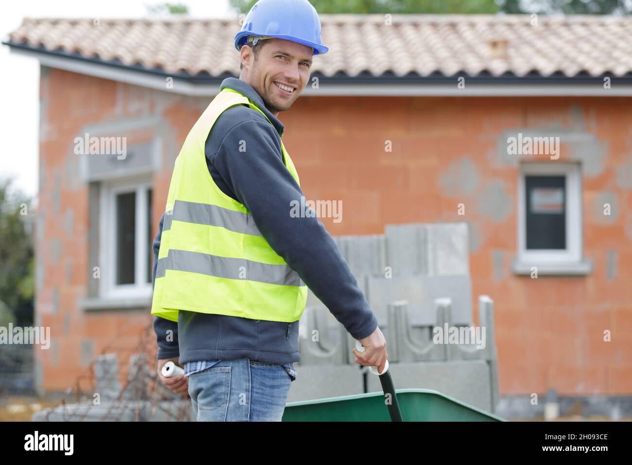 a construction worker pushing wheelbarrow Stock Photo - Alamy