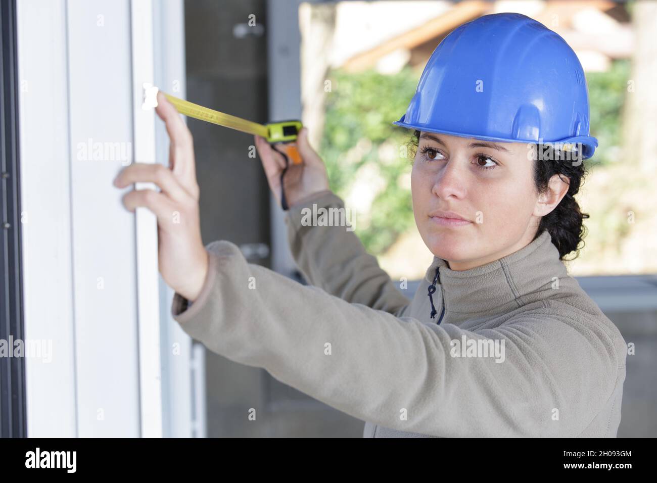 female builder measuring door frame Stock Photo - Alamy