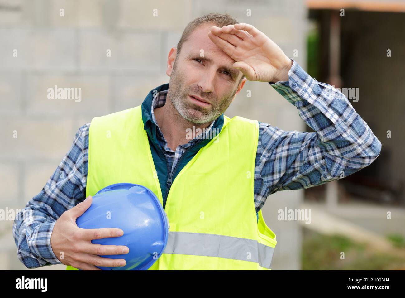 tired builder wipes the sweat from his face Stock Photo - Alamy