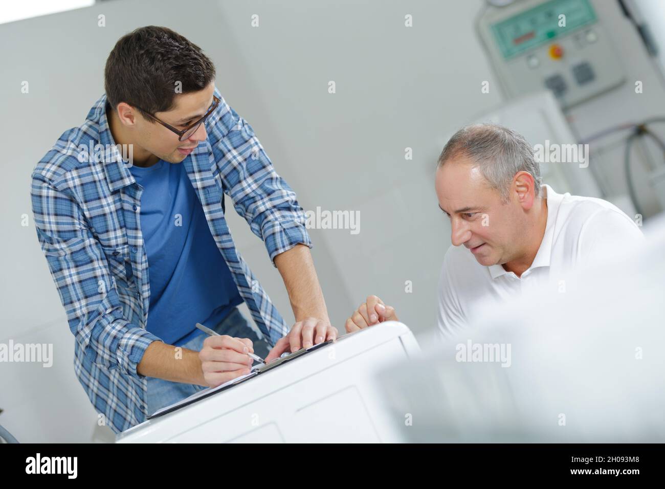team discussing in front of machine Stock Photo - Alamy