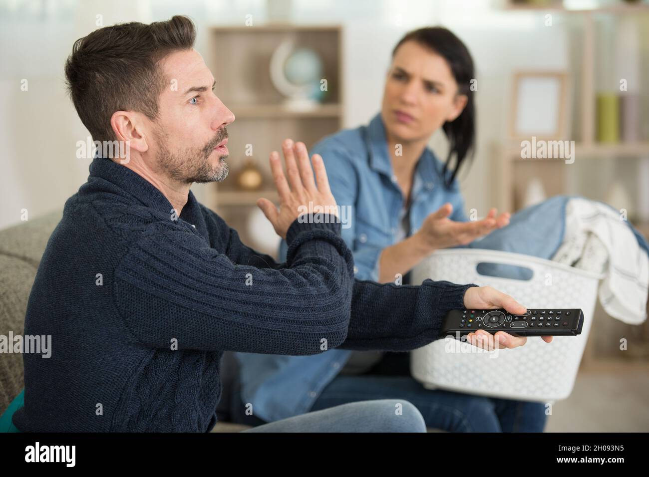 woman with washing being silenced by husband watching tv Stock Photo ...