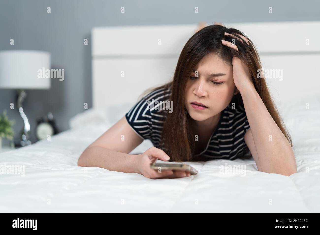 stress woman using smartphone on a bed Stock Photo - Alamy