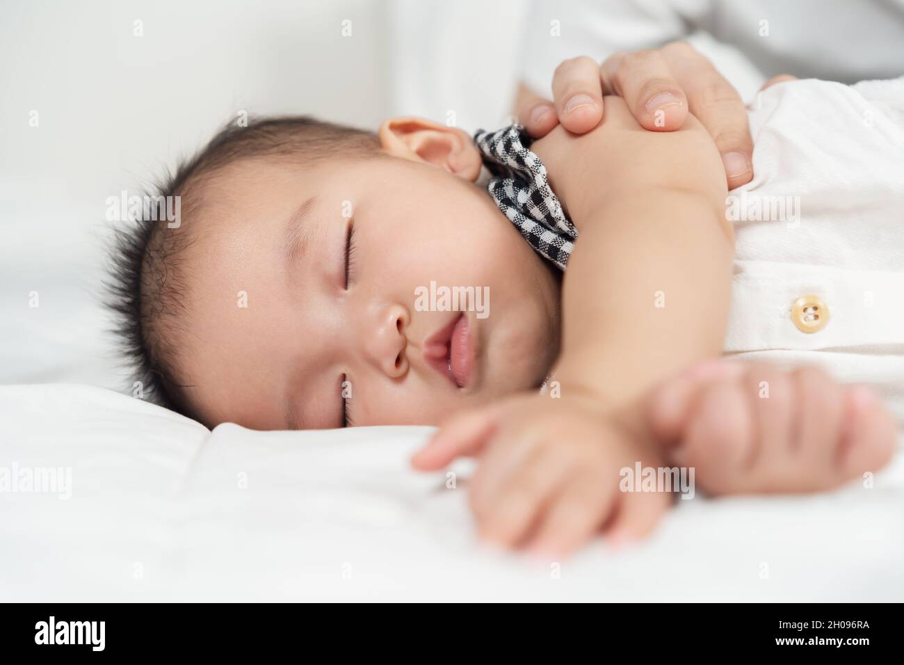 baby sleeping on a bed with hand patting Stock Photo - Alamy