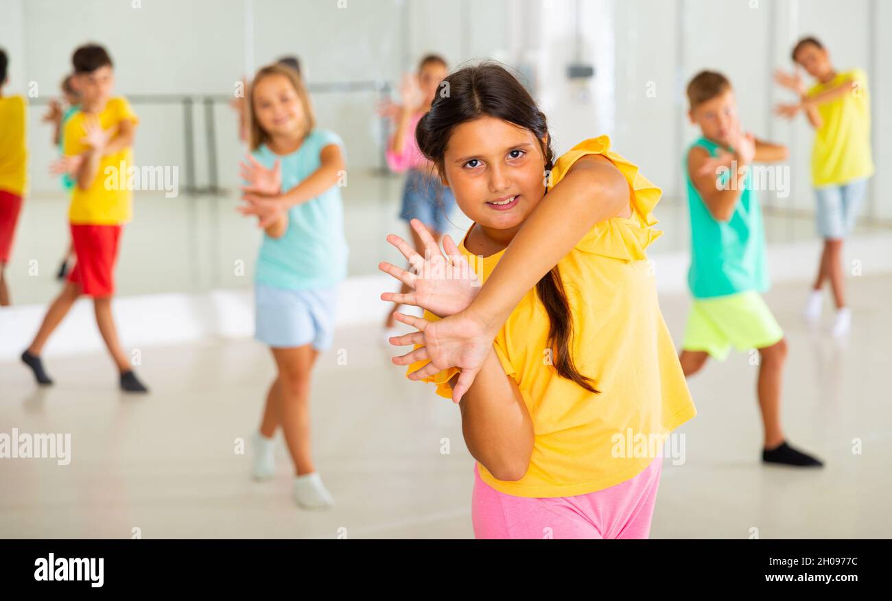 Girl exercising in group of classmates during dance class at school ...
