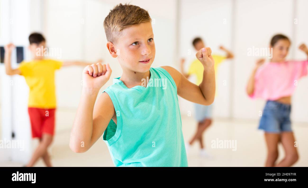 Cheerful preteen boy learning energetic dance moves in choreography ...