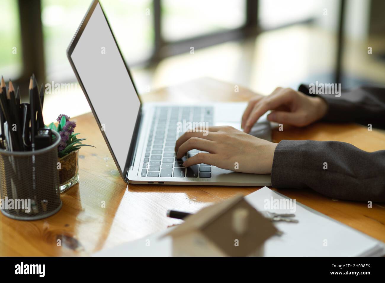 Side view of a female realtor working on laptop computer, typing rental ...