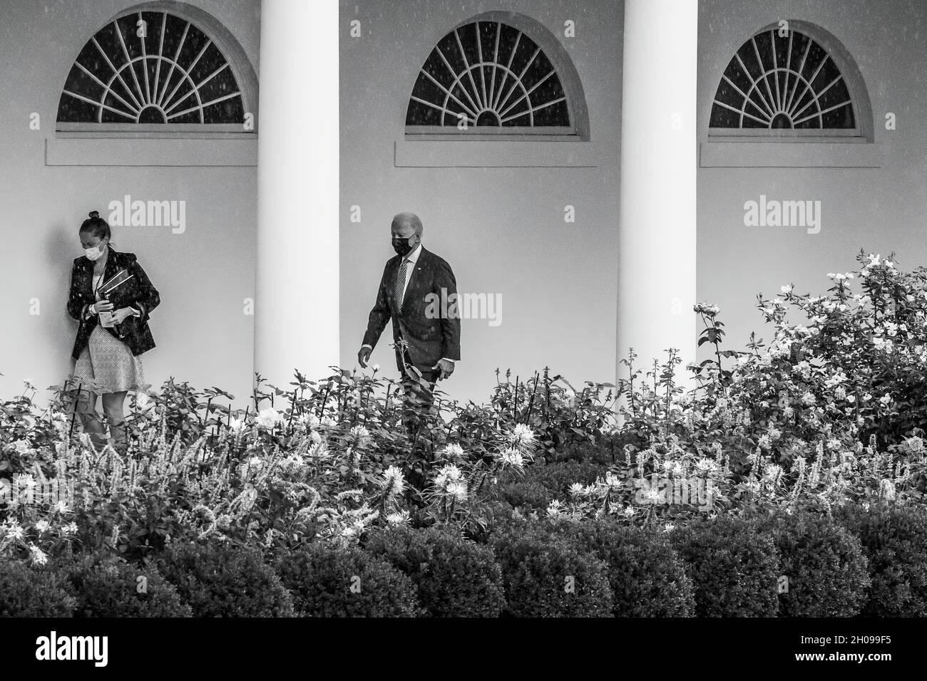 Rain falls as President Joe Biden walks along the Colonnade of the ...