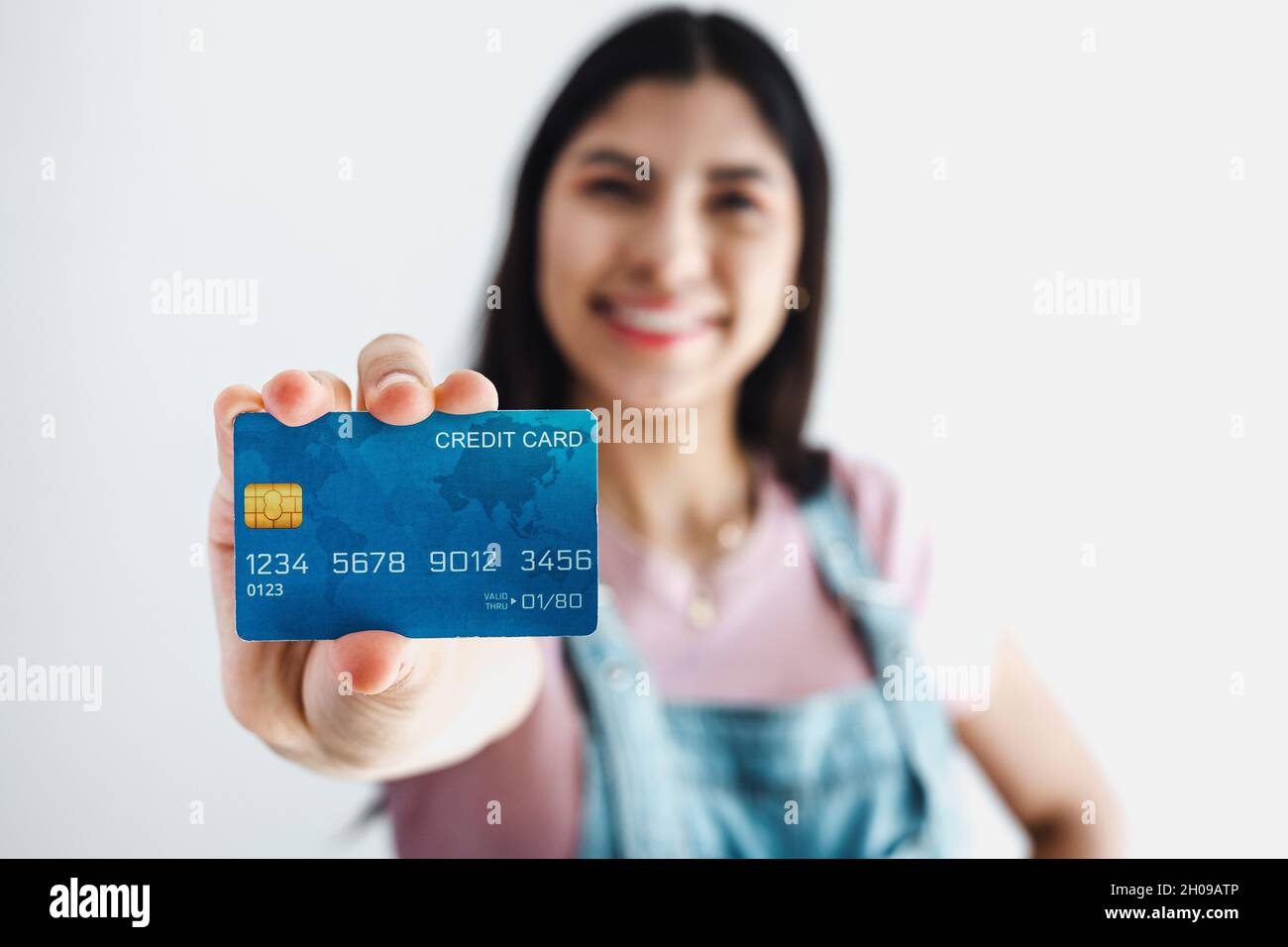 Young hispanic woman holding blue credit card isolated over white ...