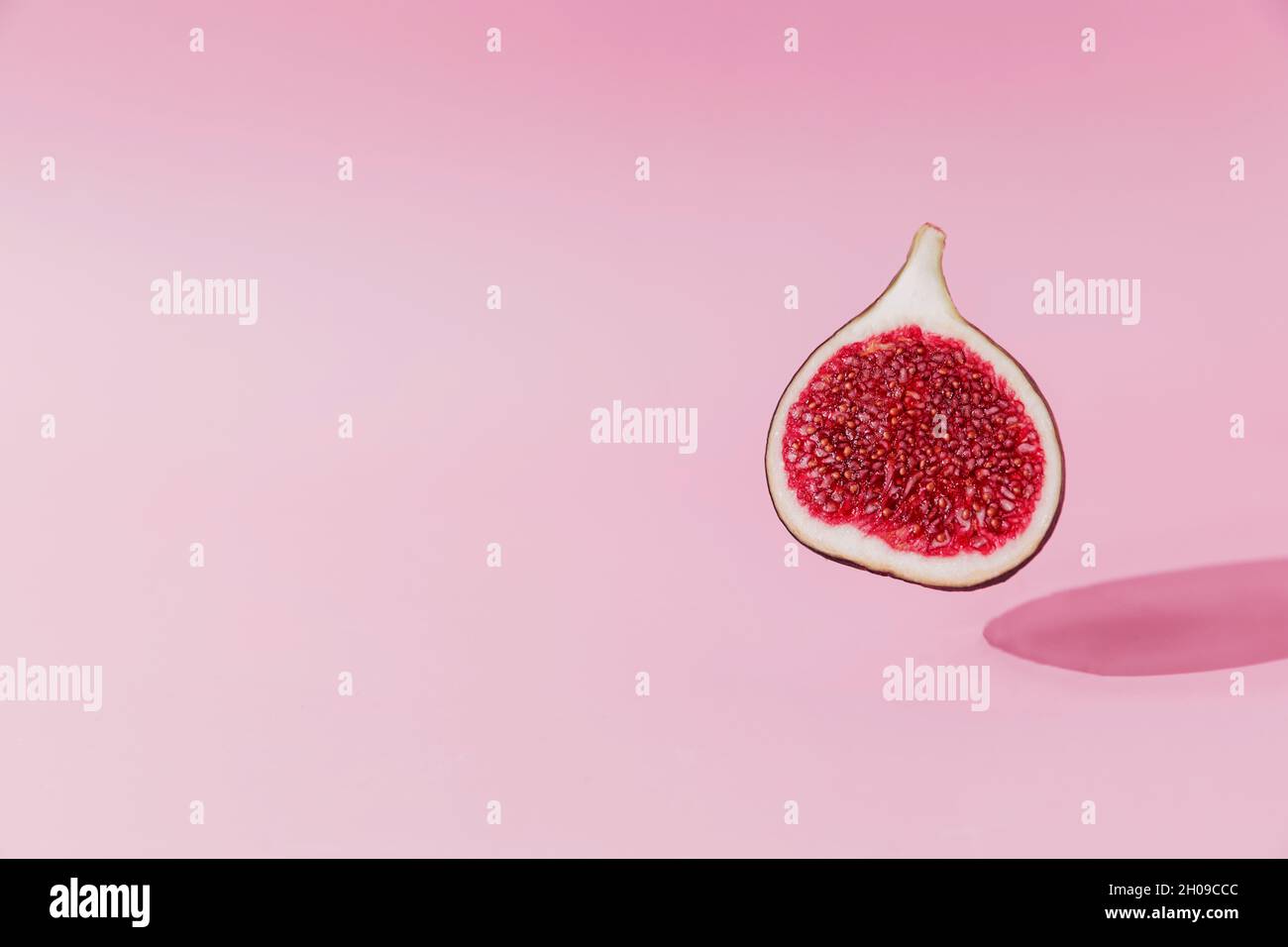 Fresh tasty fig fruit halve levitation with shadow on pink background ...