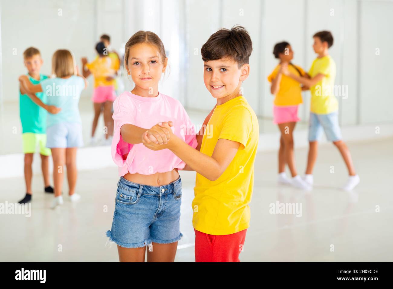 Tween boy and girl practicing slow pair dancing during group class ...