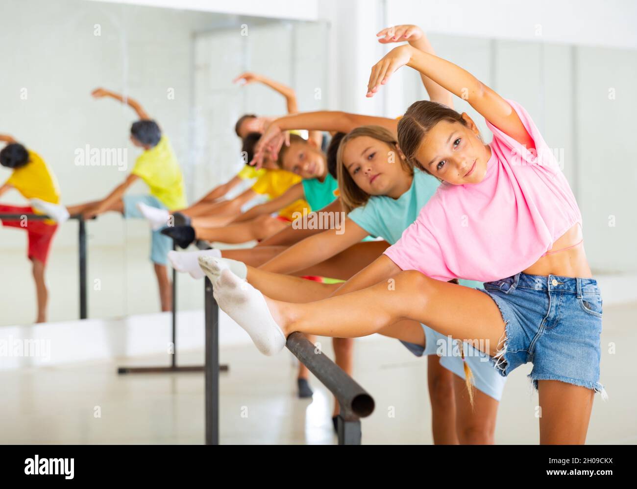 Diligent tween girl practicing classic dance moves near ballet barre ...