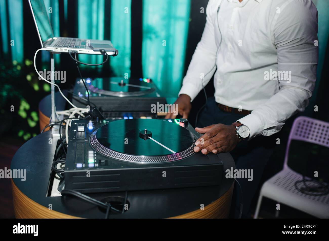 Close up of DJ console at the party. Neon lights over the hands of ...