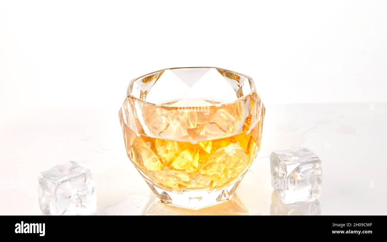 Glass of whiskey with ice cubes on white background with reflection ...