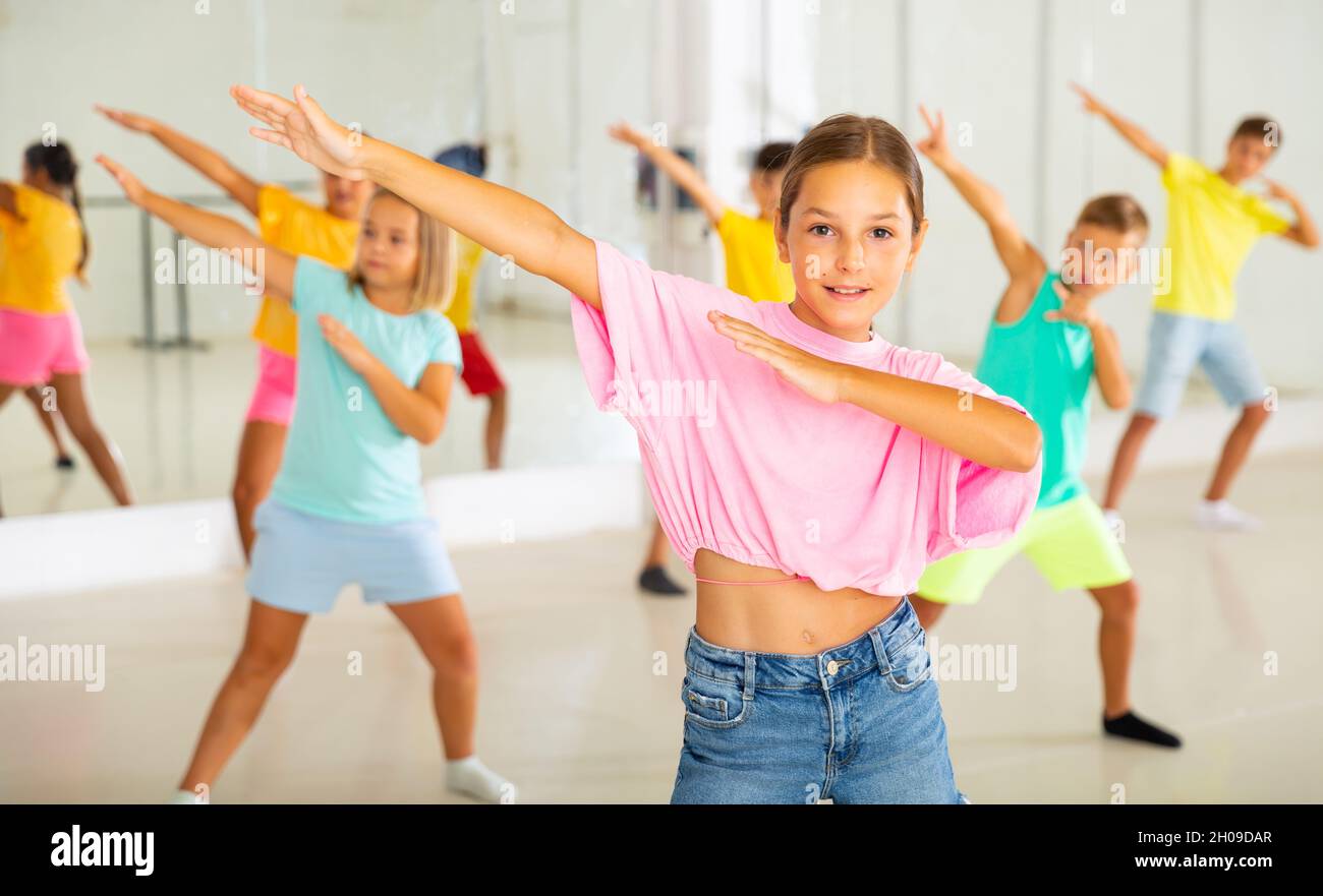 Girl exercising in group of classmates during dance class at school ...
