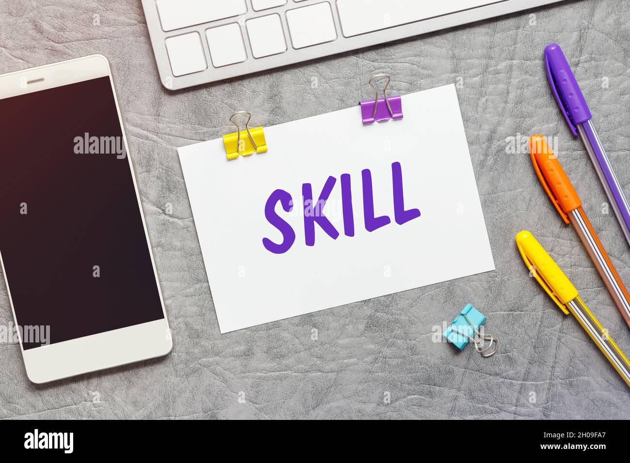 A paper note with the text of the SKILL, keyboard and a smartphone ...