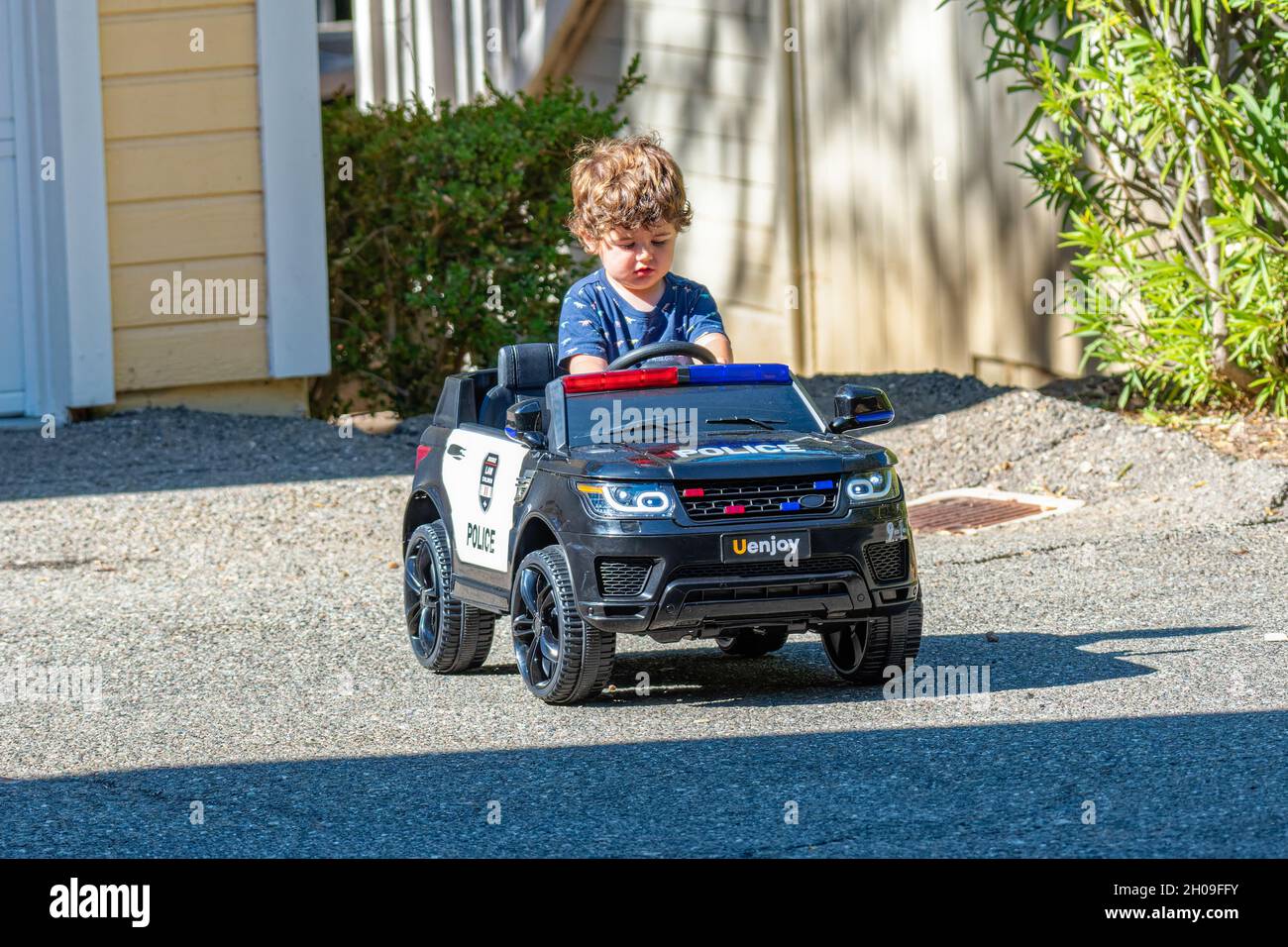 Cute little toddler boy having fun riding battery powered police toy ...