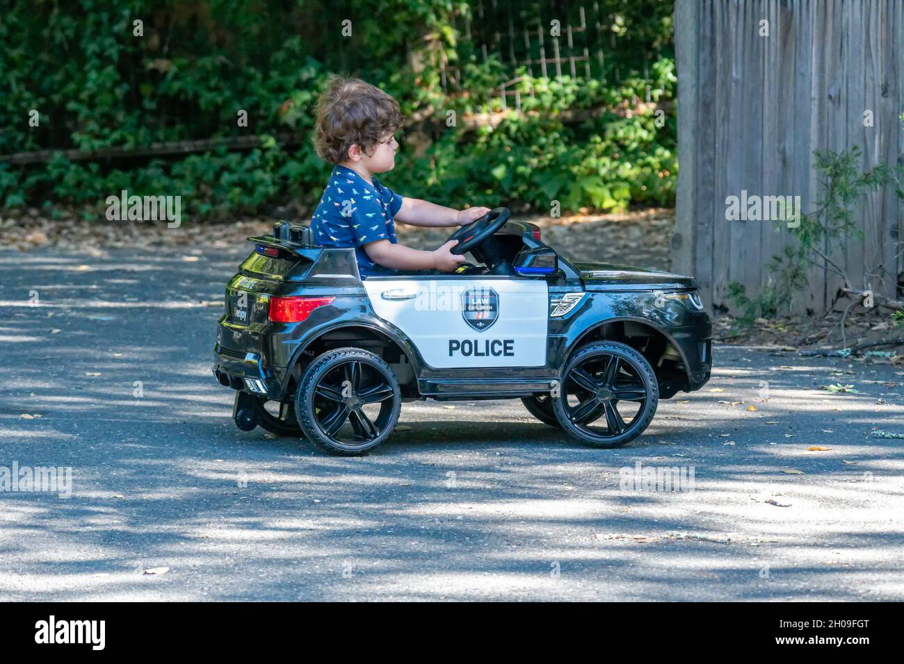 Cute little toddler boy having fun riding battery powered police toy ...