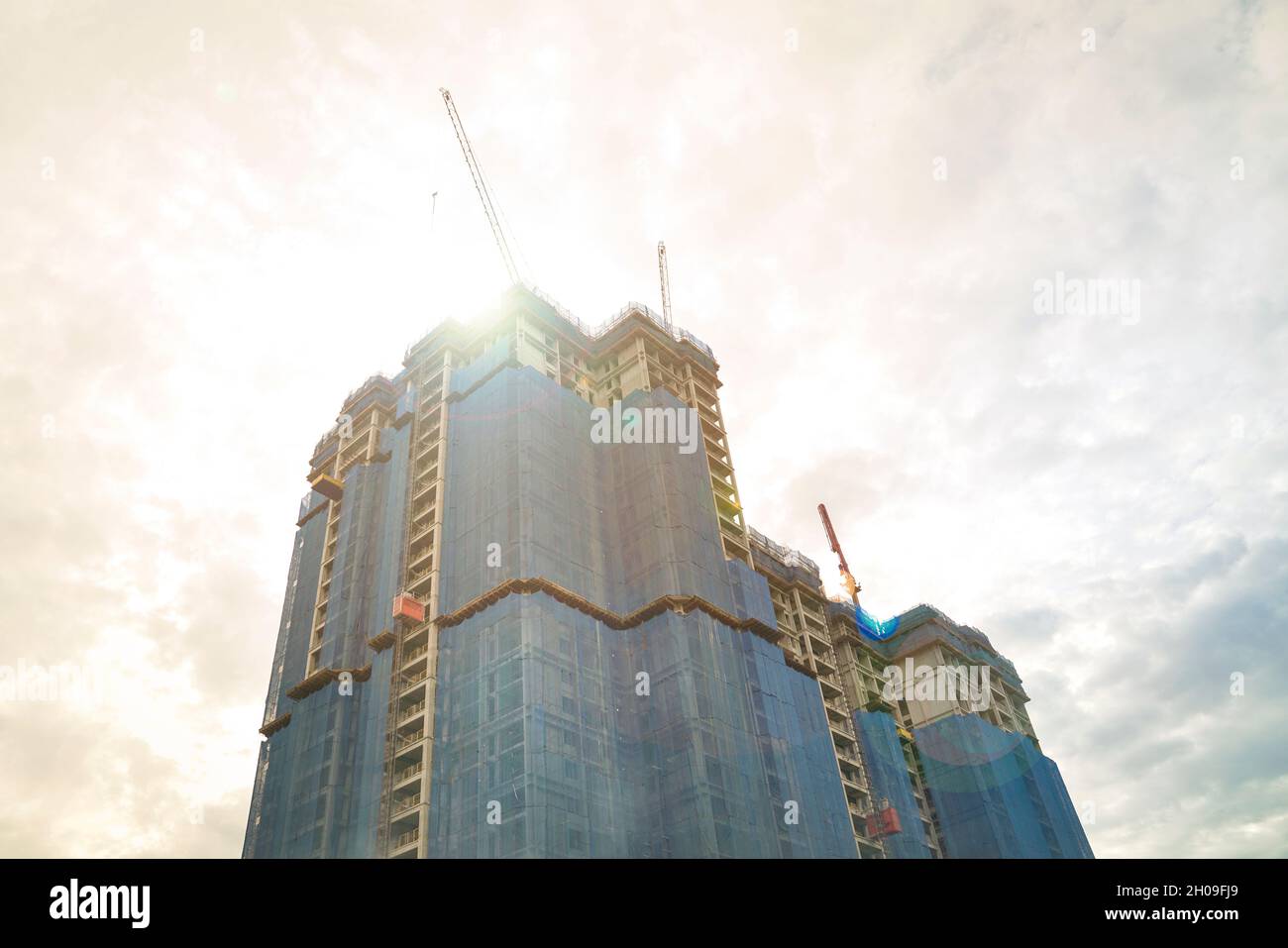 Crane and high rise building under construction with lens flare Stock ...
