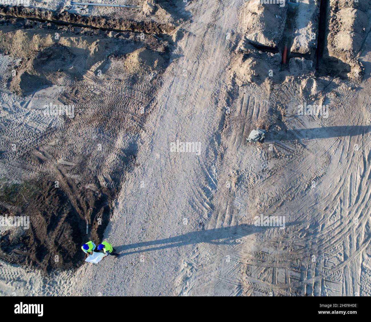 Aerial image of two engineers with helmets and vests, holding ...