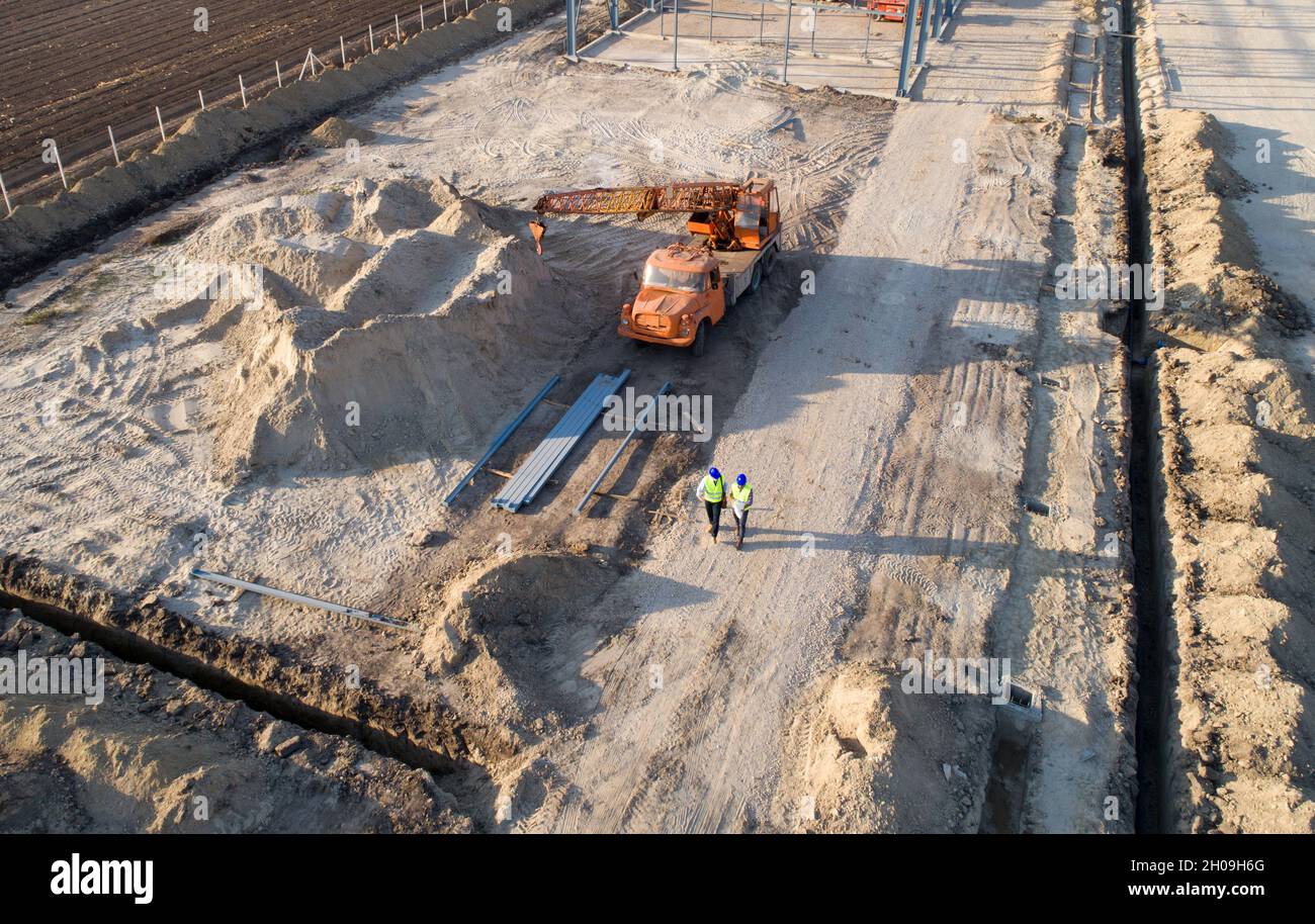 Aerial image of two engineers with helmets and vests, holding ...