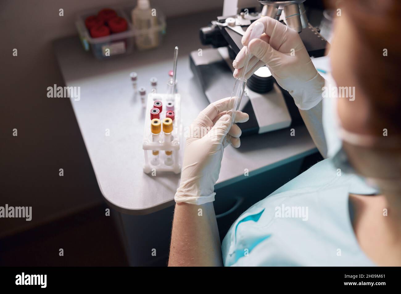 Female lab tech takes sample from test tube to research material at ...