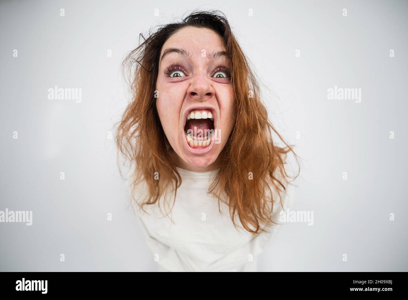 Close-up portrait of insane woman in straitjacket on white background ...