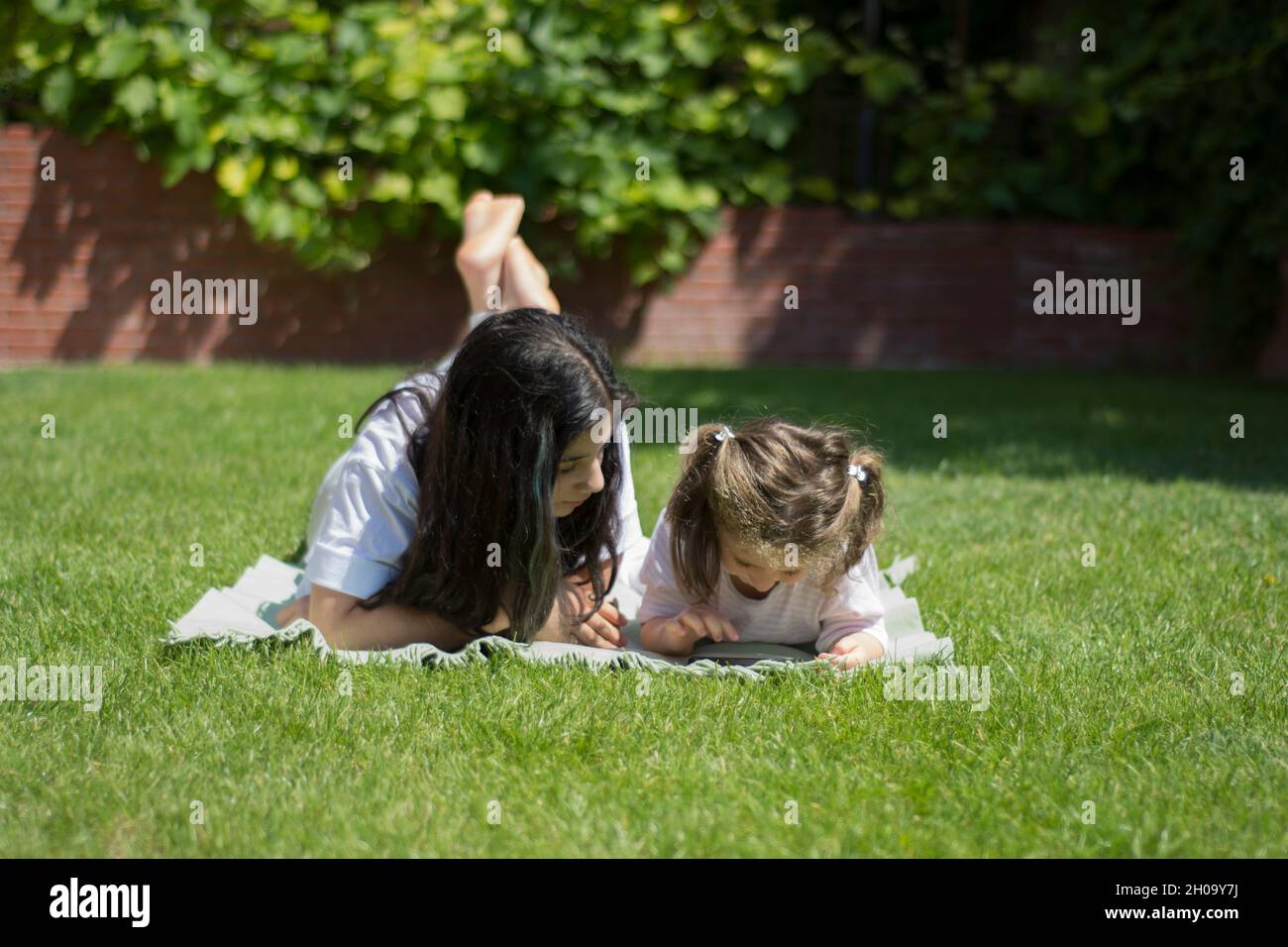 two little girls are playing on the lawn in the garden of their house ...