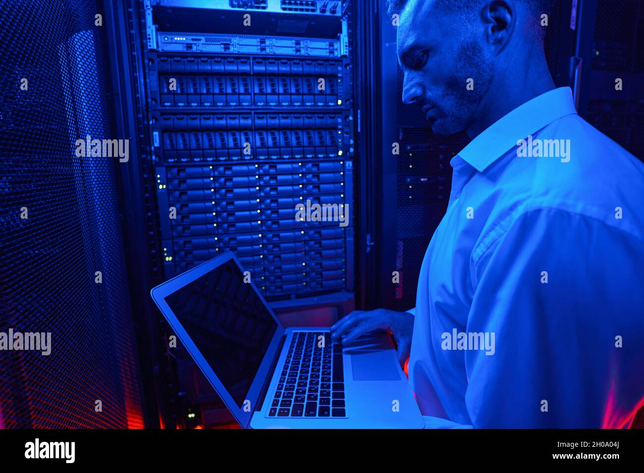 System administrator troubleshooting server rack with laptop Stock ...