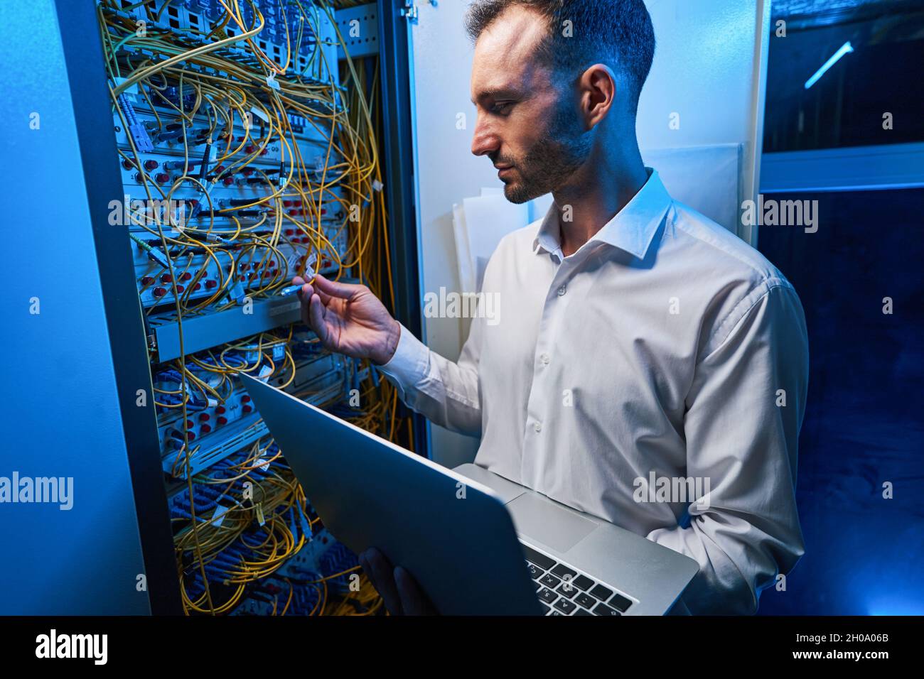Male server administrator inserting cable into network switch Stock ...