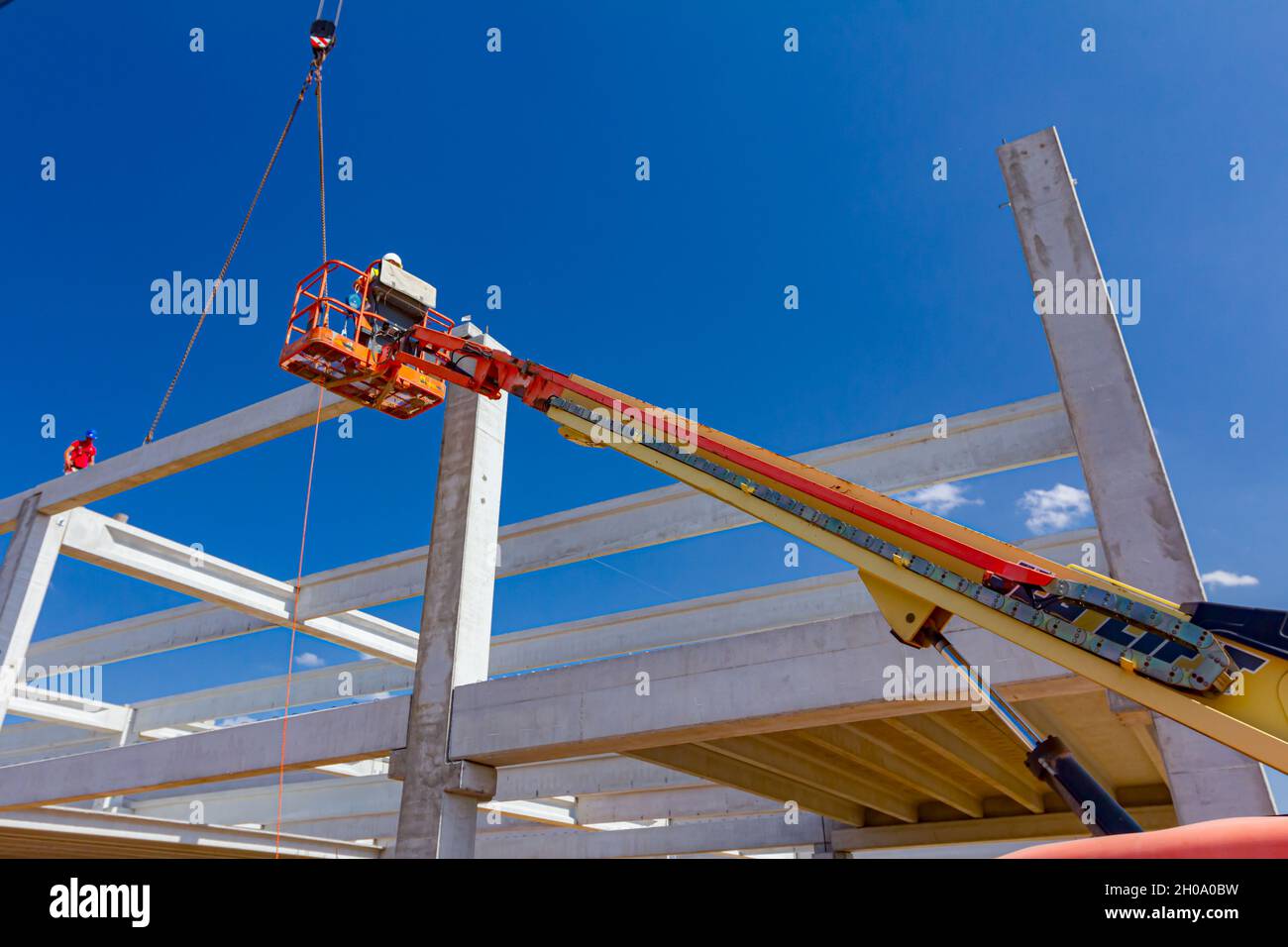 Mobile crane is operating and worker is assembly concrete joist in high ...