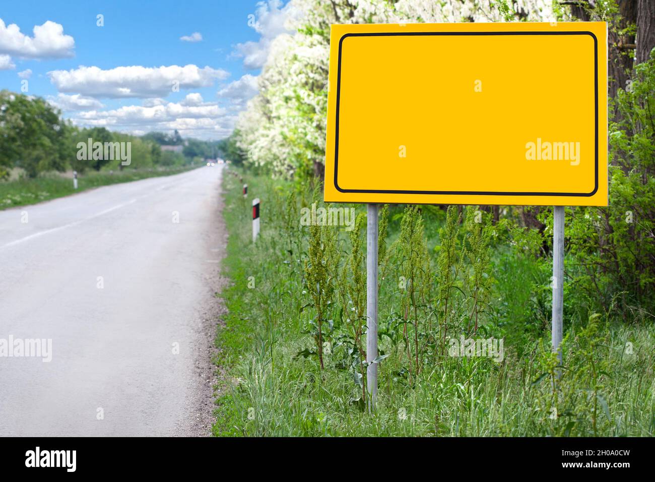 Blank yellow sign along the road for place name on a beautiful spring ...