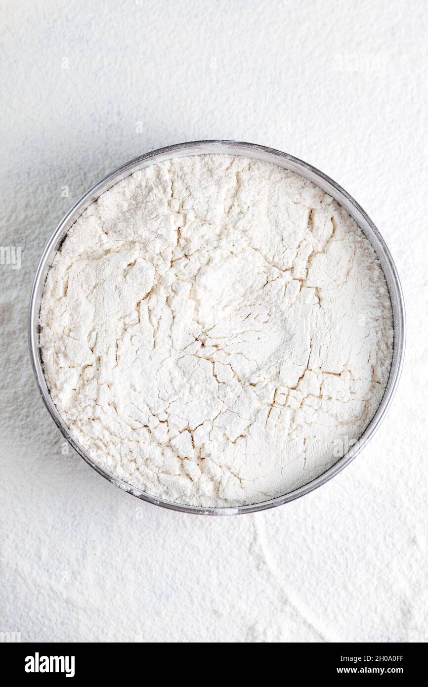 Flour in round metal bowl and scattered around on background. Flour ...