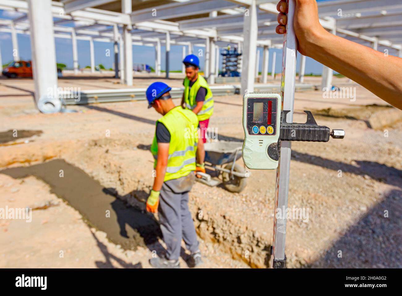 Construction worker is holding leveling rod to help surveyor, geodesist ...