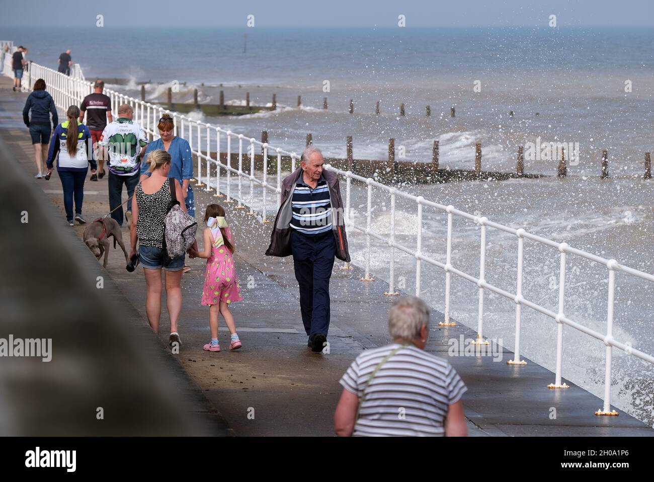 Seafront walk at high tide with waves splashing people Stock Photo - Alamy