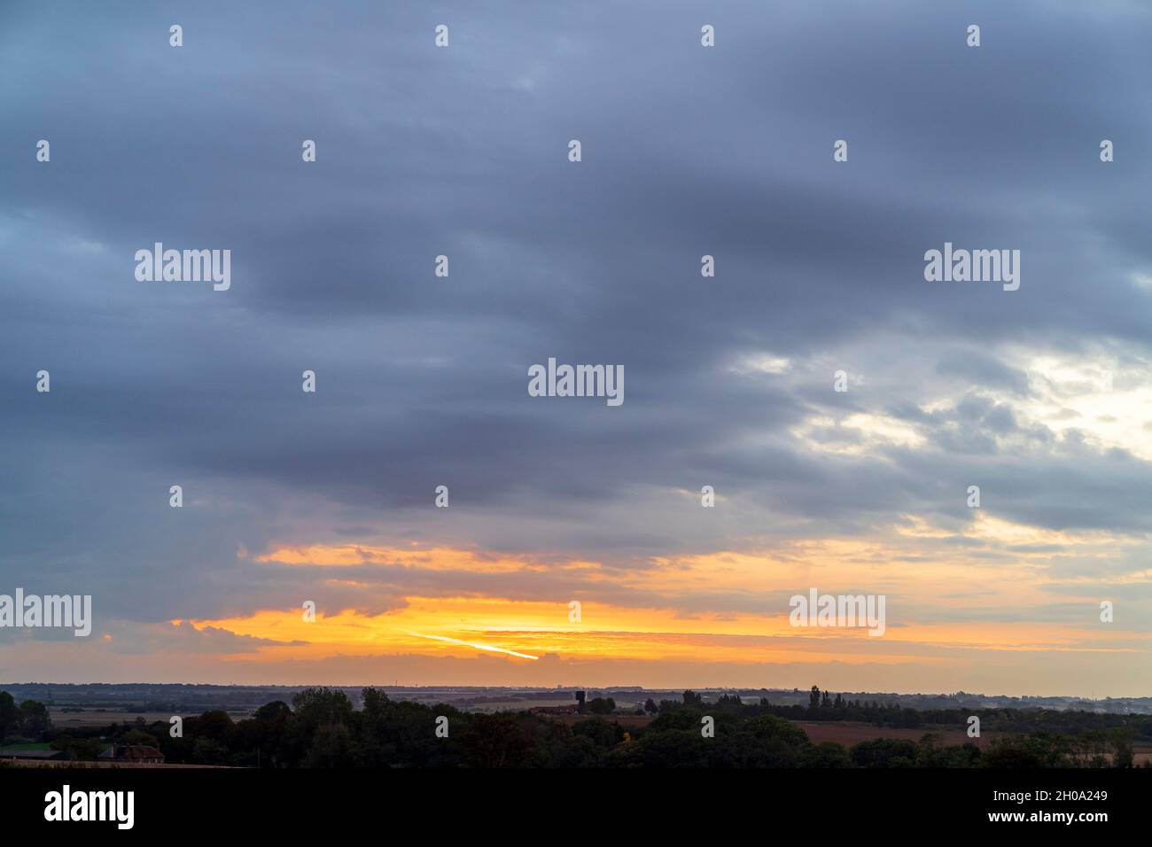 Sunrise hidden behind thick broken clouds, stratocumulus, over the Kent ...