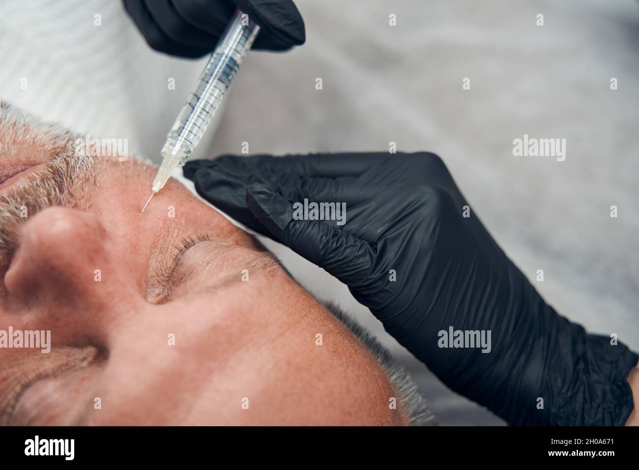 Man getting injection in cheek in cosmetology clinic Stock Photo - Alamy