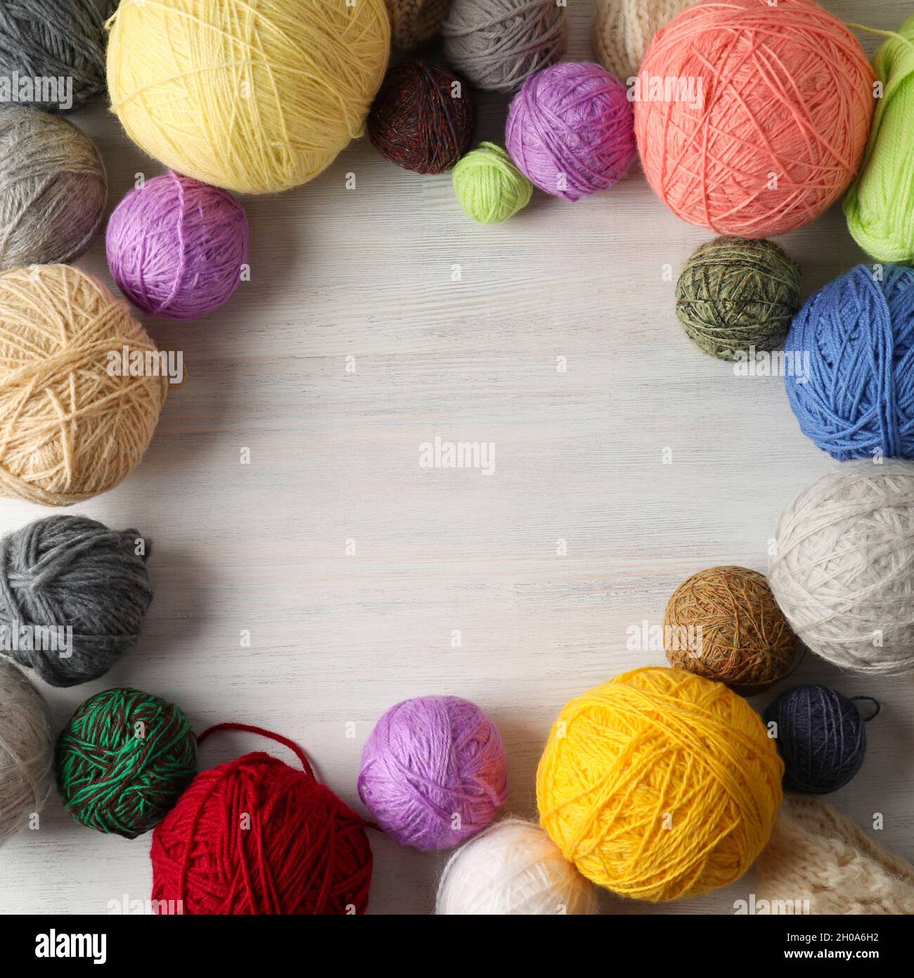 Multi colored balls of yarn on white wooden background Stock Photo - Alamy