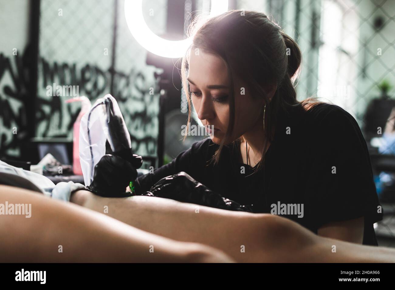 Professional female tattoo artist makes a tattoo in the studio, close ...