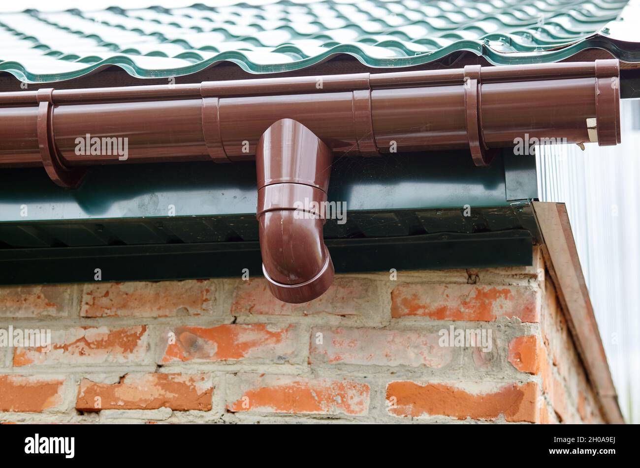 Facade of a suburban building with downspout. View of the roof against ...